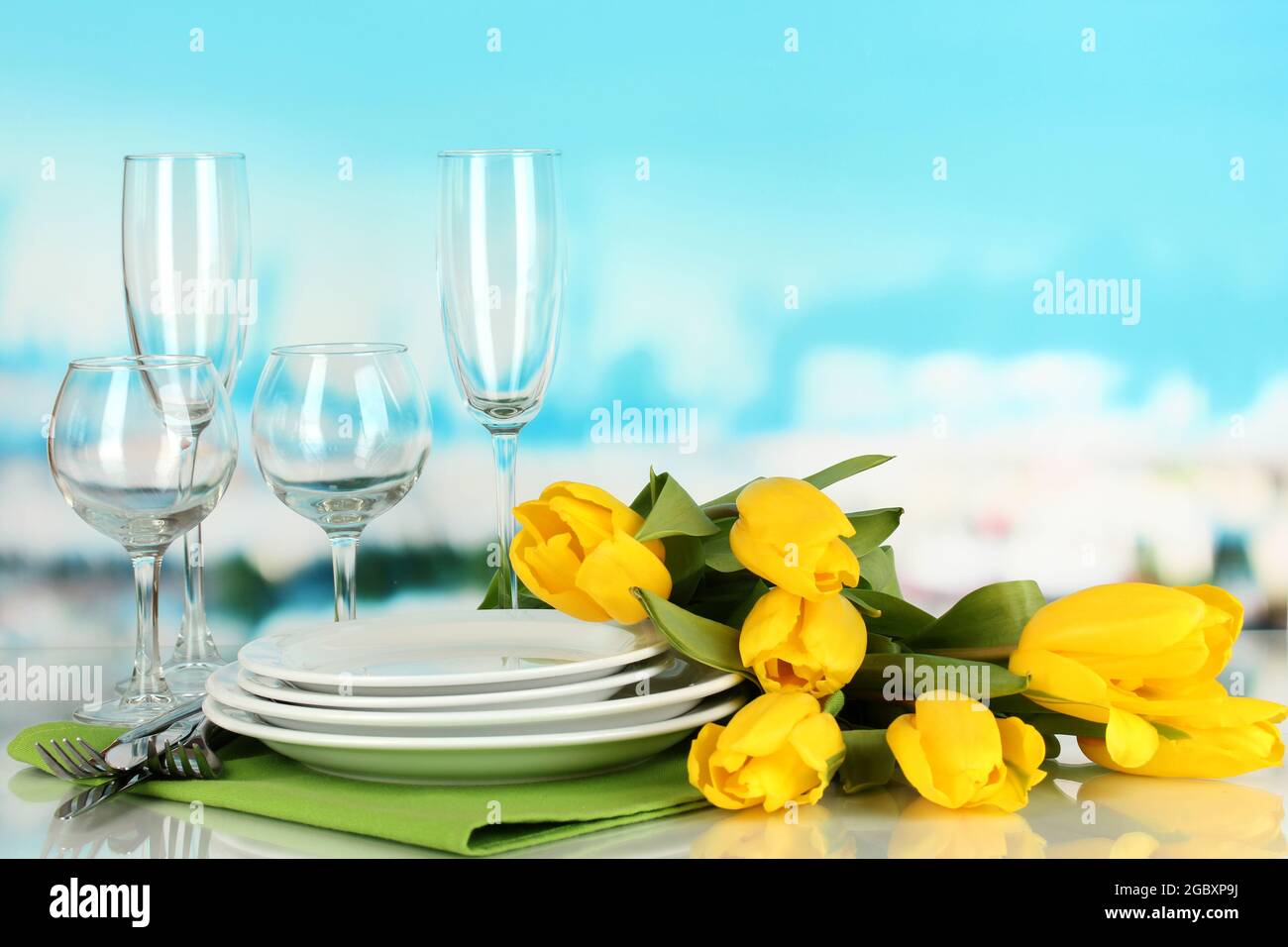 Yellow tulips and utensils for serving on blue natural background ...