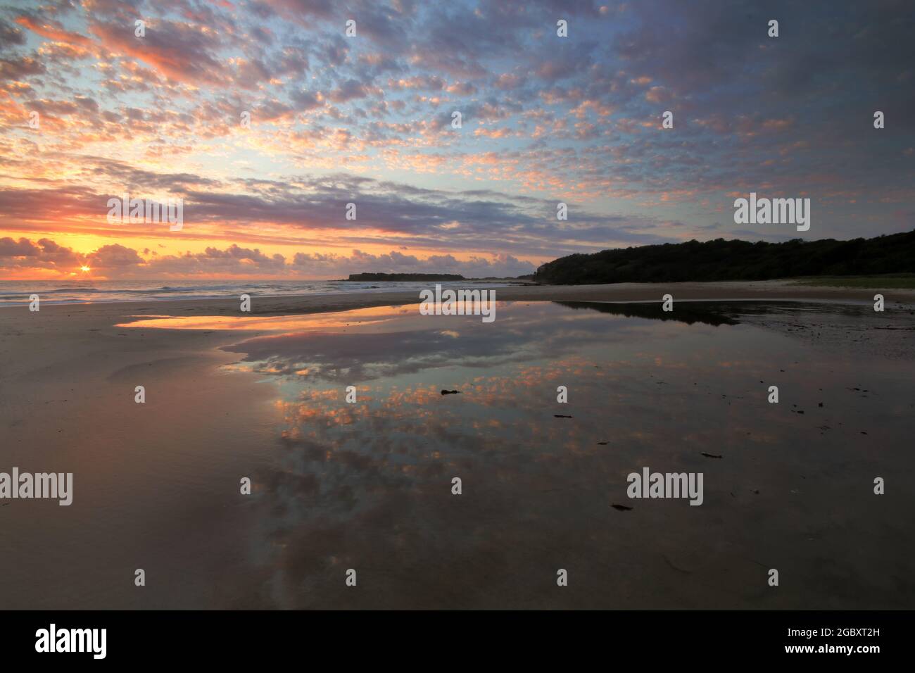 sunrise reflections on the beach Stock Photo - Alamy