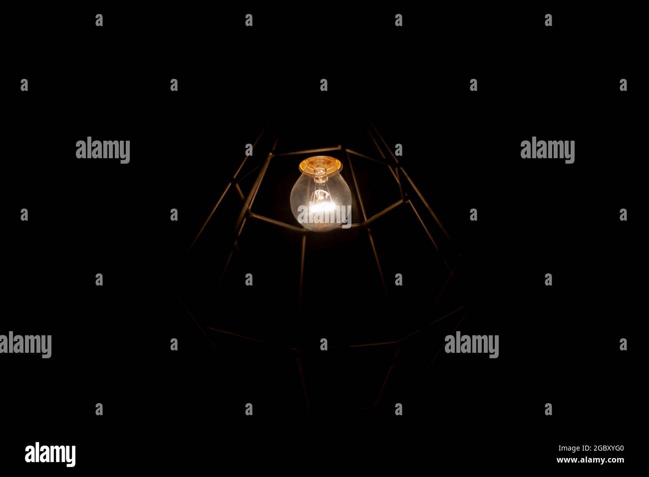 The gloomy light in the room. The lamp under the ceiling on the cord. A ...