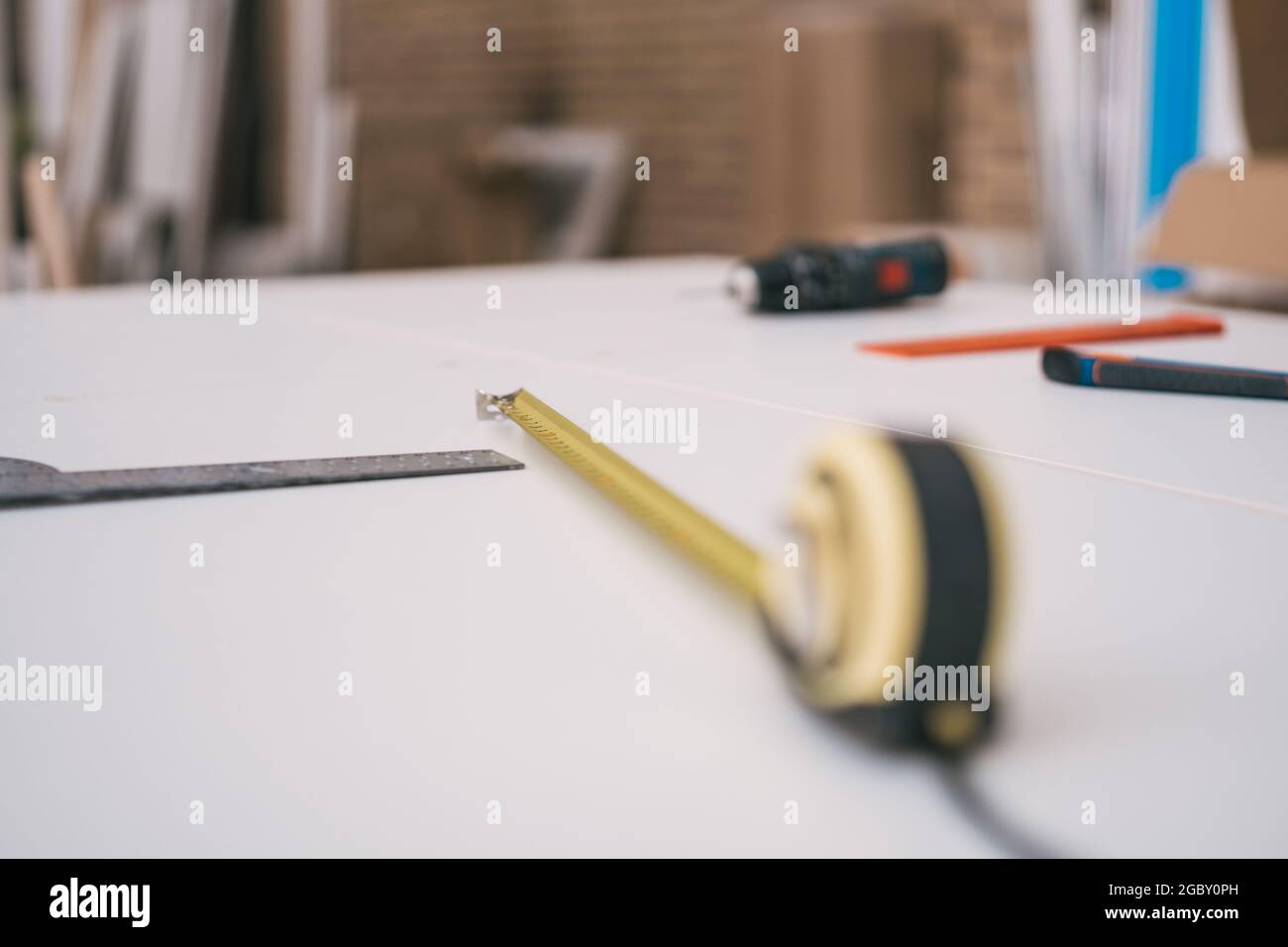 Tape measure and square on a white table of a workshop Stock Photo - Alamy