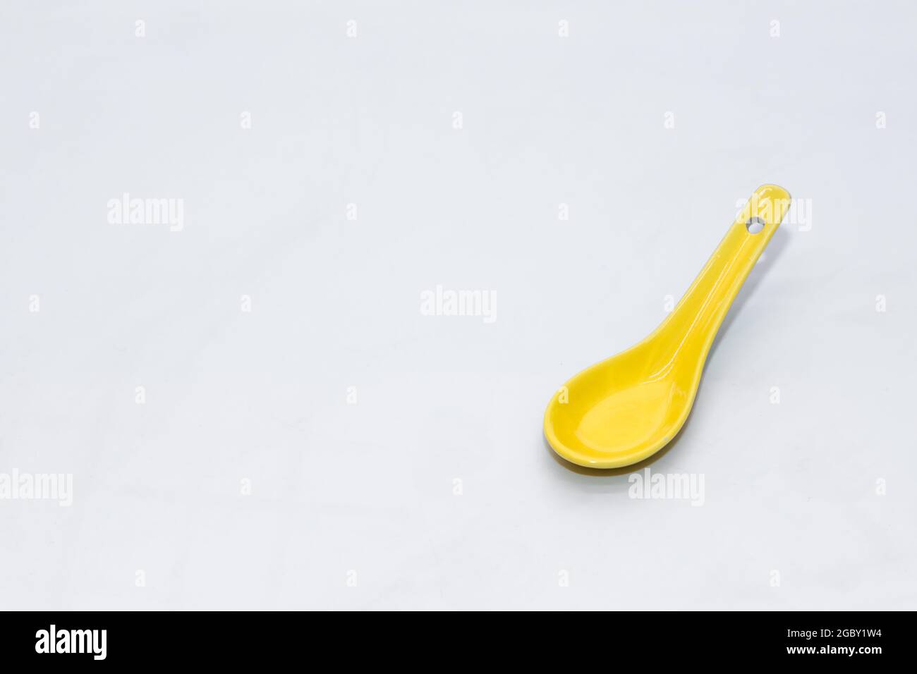 A yellow spoon against white background with copy space Stock Photo - Alamy