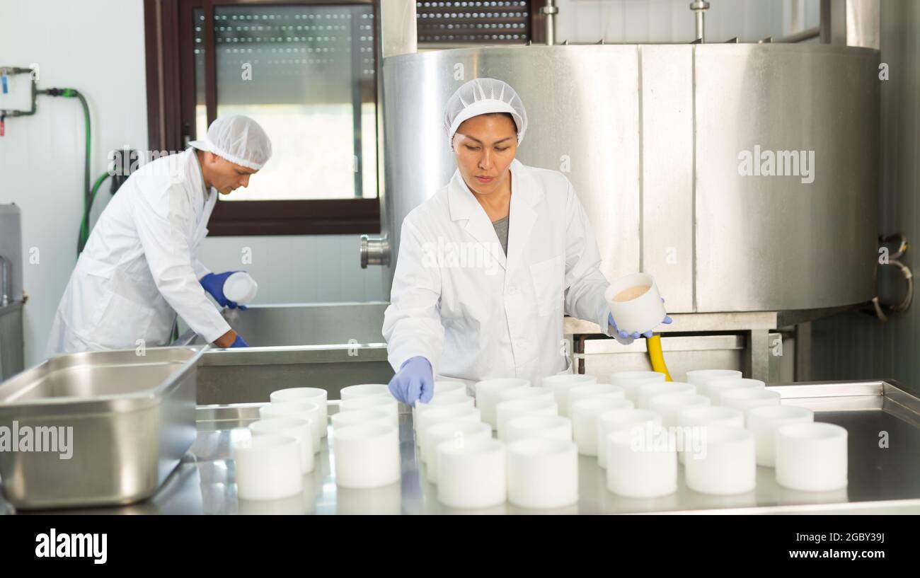 Woman wearing uniform showing cottage cheese production process on ...