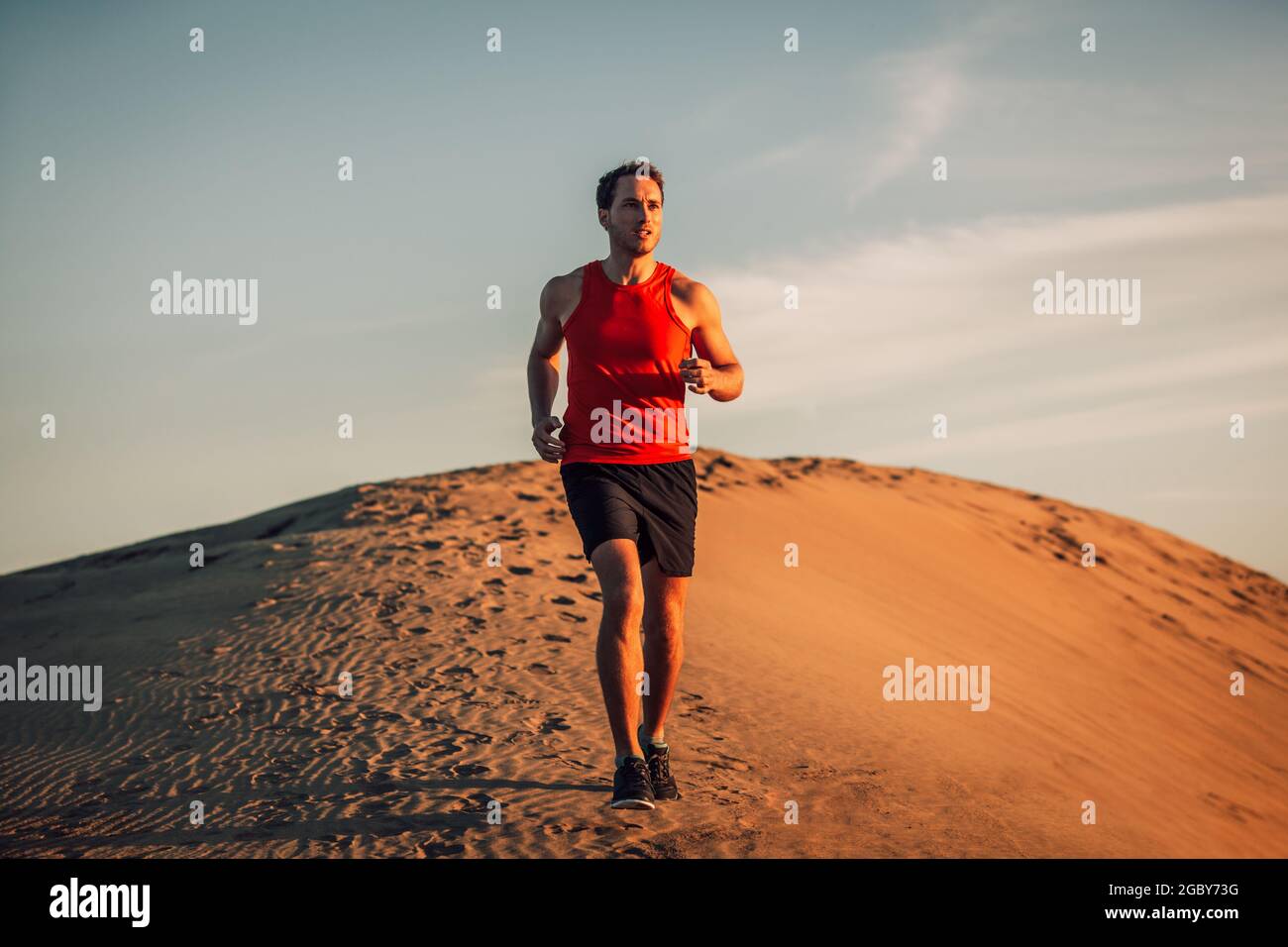 Trail runner athlete running man in desert sand dun in heat of summer ...