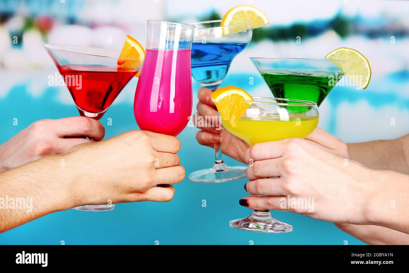 Cocktails in hands on pool background Stock Photo - Alamy