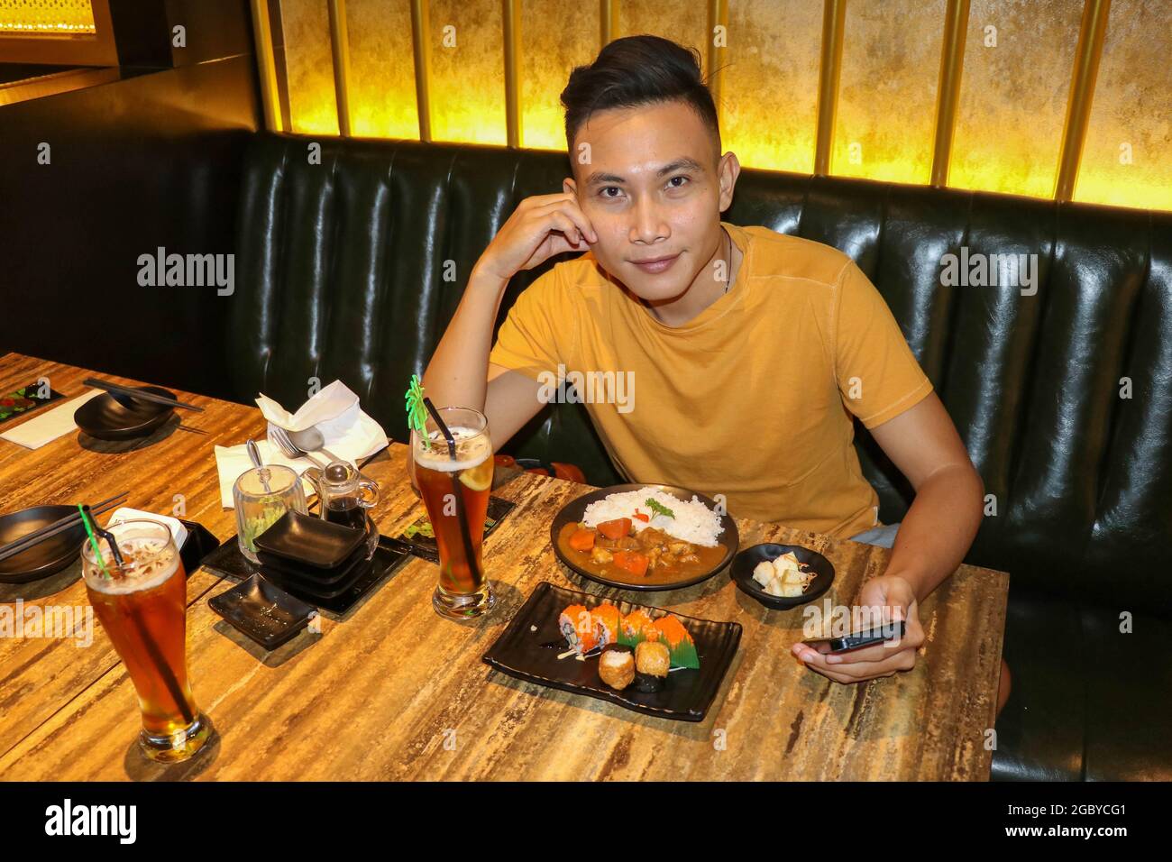 An attractive asian man eating at a restaurant. Portrait young handsome ...
