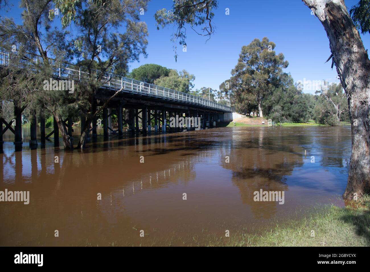 Old bridge over muddy river in flood with blue sky Stock Photo - Alamy