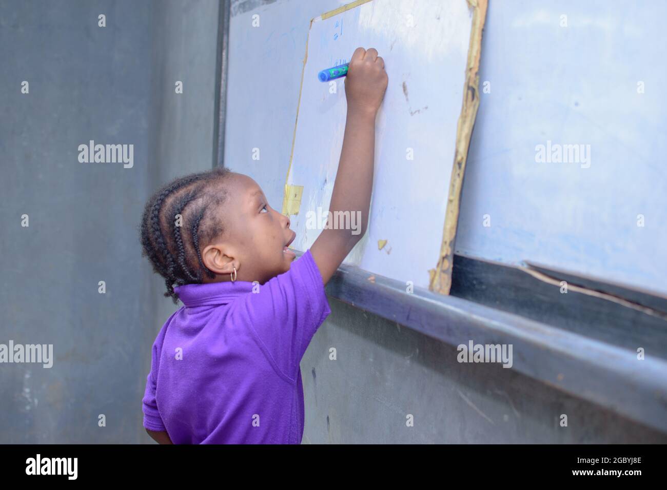 African girl child, pupil or student standing in a classroom and ...