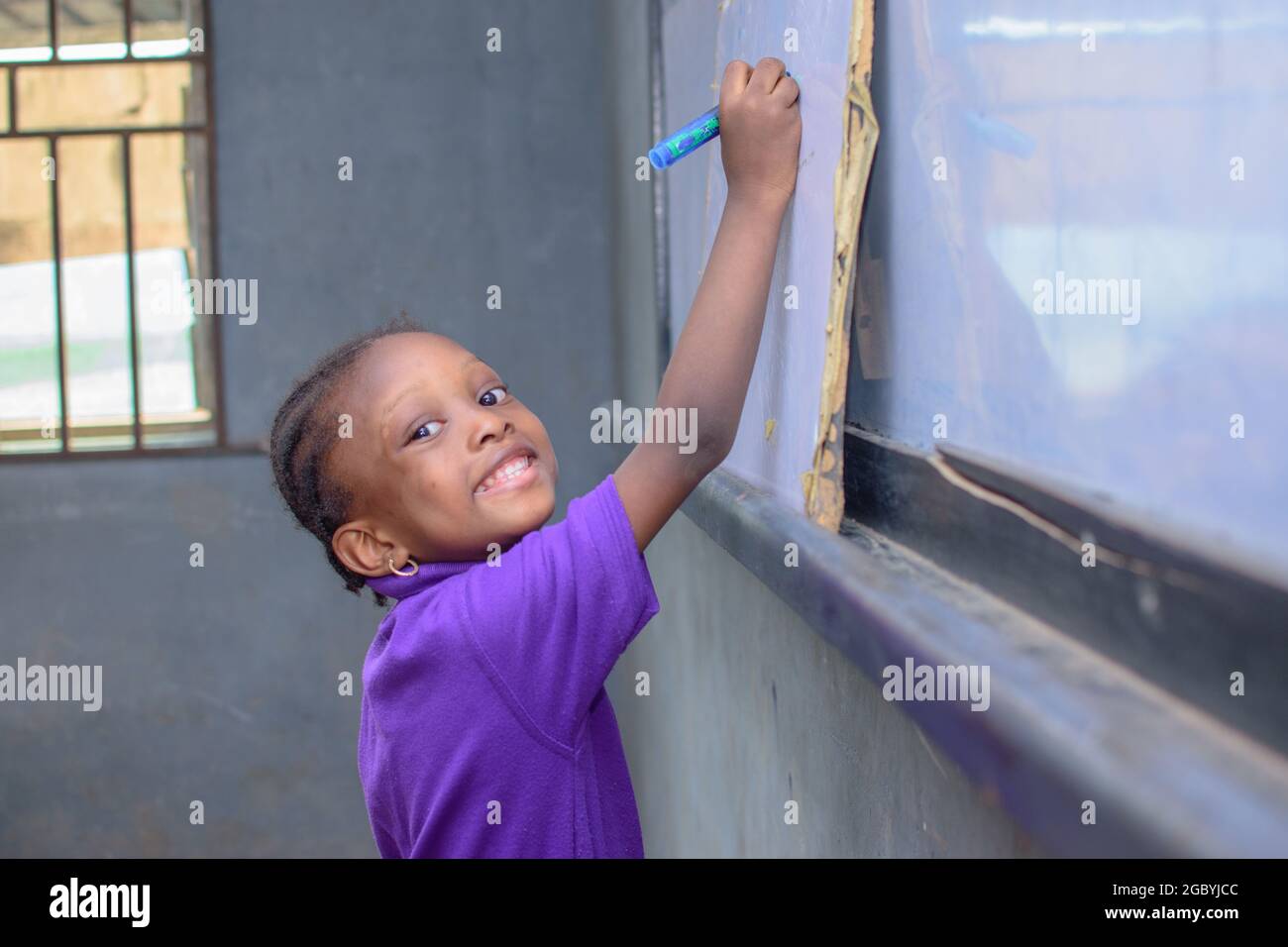 African girl child, pupil or student standing in a classroom and ...
