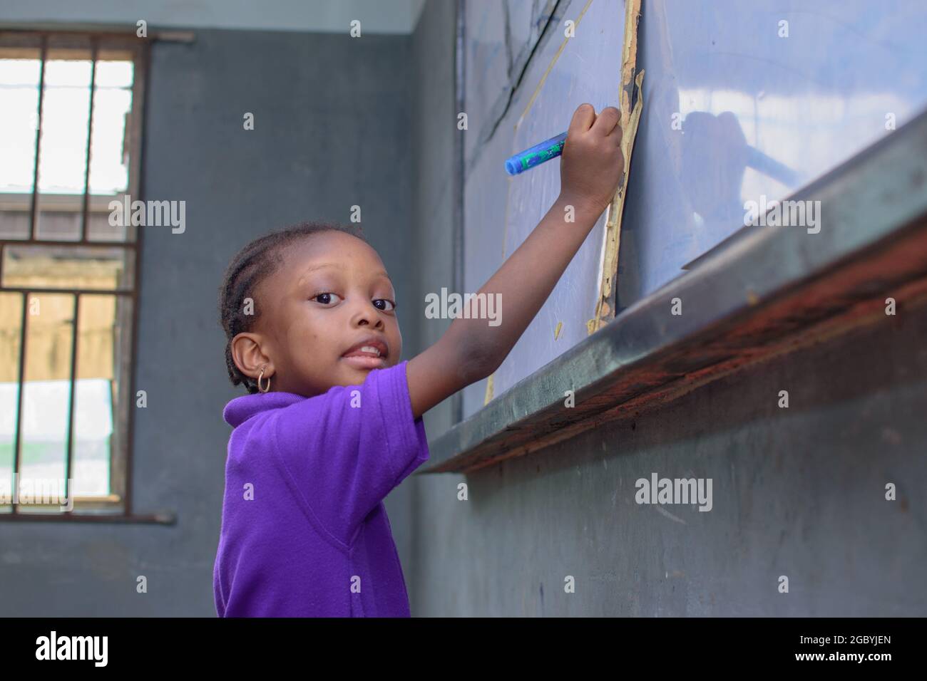 African girl child, pupil or student standing in a classroom and ...