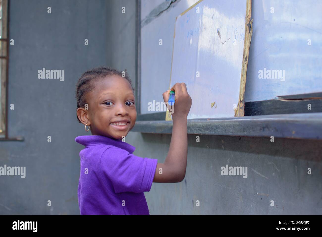 African girl child, pupil or student standing in a classroom and ...