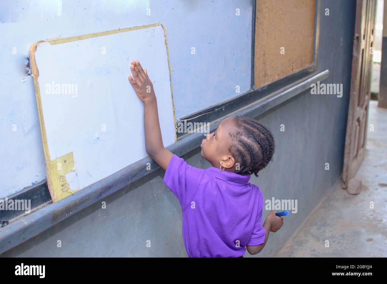 African girl child, pupil or student standing in a classroom and ...