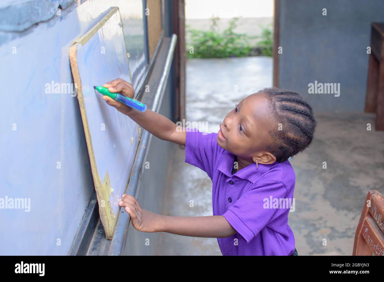 African girl child, pupil or student standing in a classroom and ...