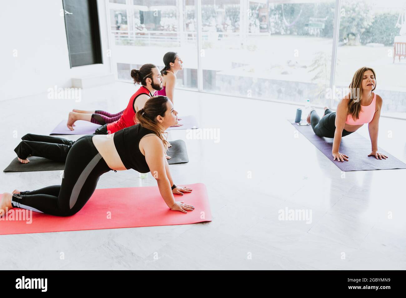 Young mexican people with instructor practicing yoga stretching ...