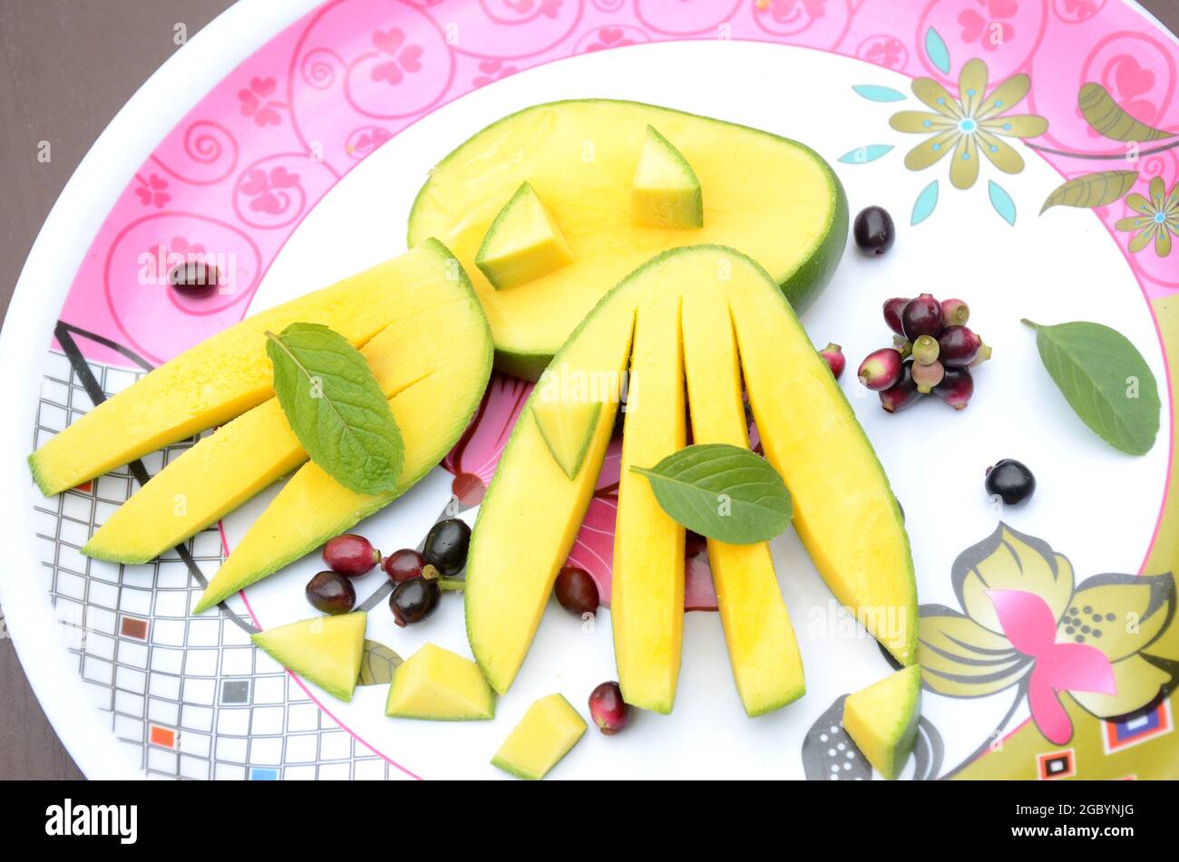 closeup the sliced ripe green yellow mango fruit with green j amble fruit and mint leaves over ...