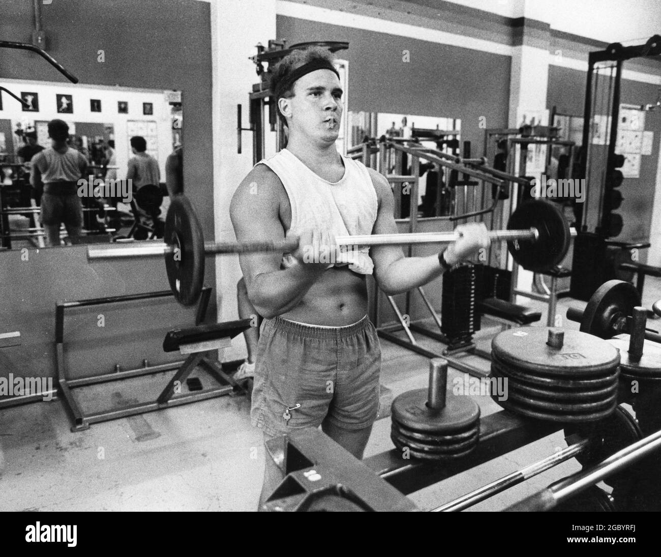 Austin Texas USA, circa 1987: Young man uses free weights to do biceps ...