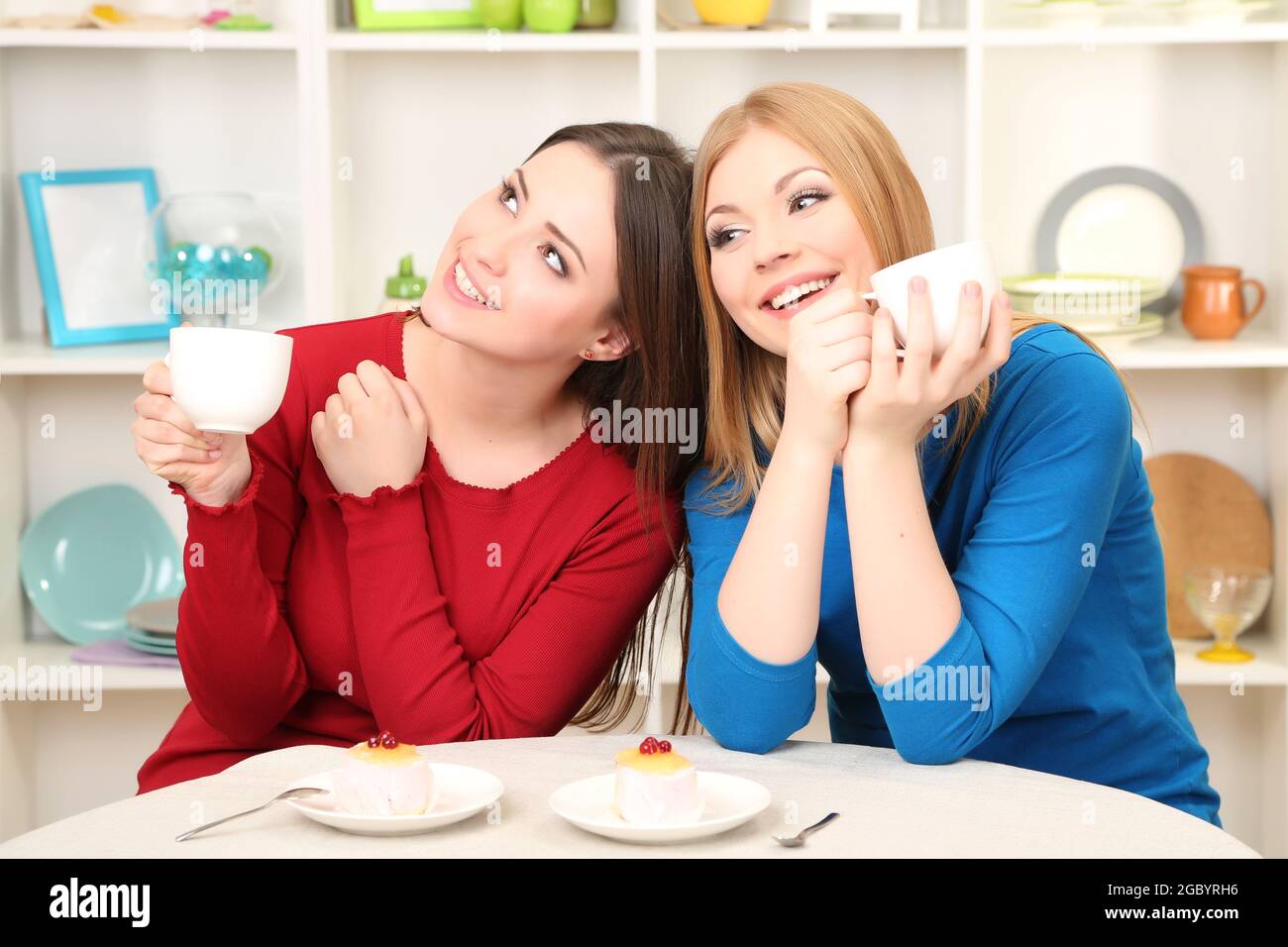 Two girl friends talk and drink tea in kitchen Stock Photo - Alamy