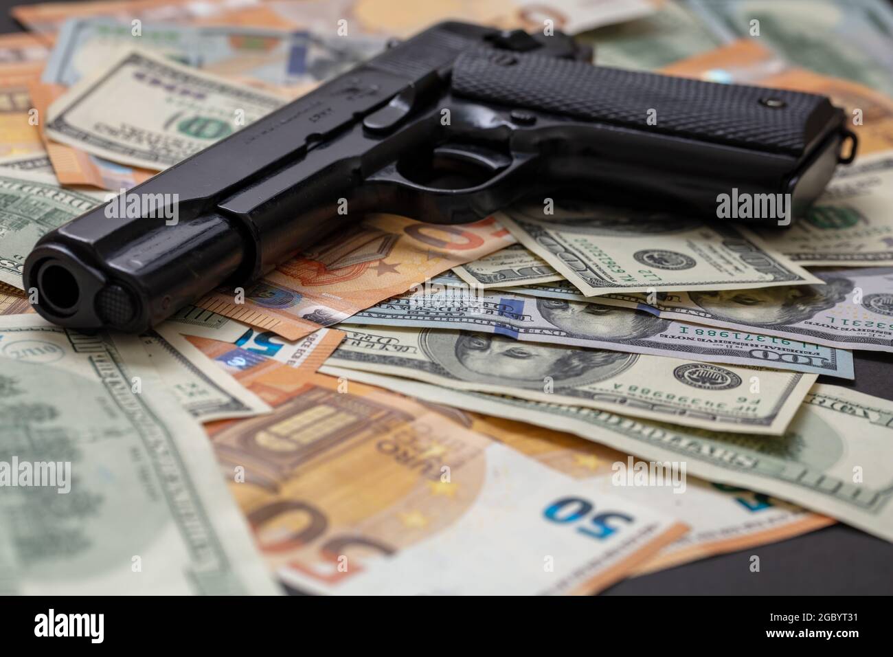 Pistol on dollar and euro banknotes background, closeup view. Criminal ...