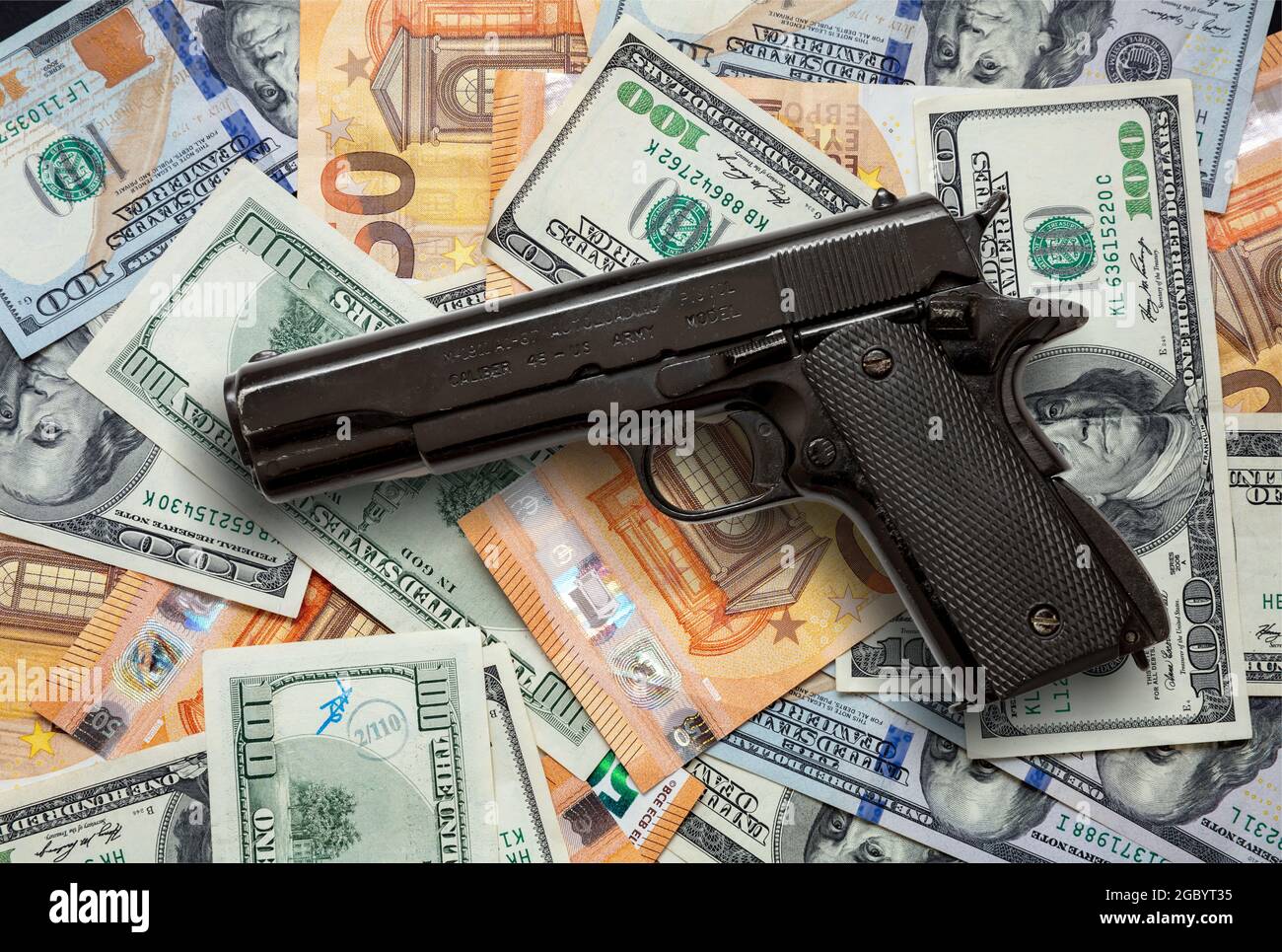 Criminal money. Pistol on dollar and euro banknotes background, top ...