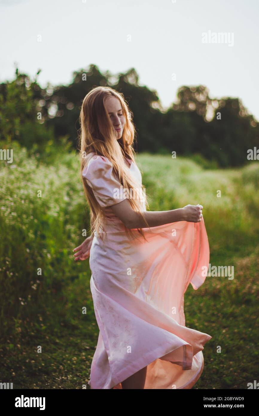 girl dancing in the field in a pink dress Stock Photo - Alamy