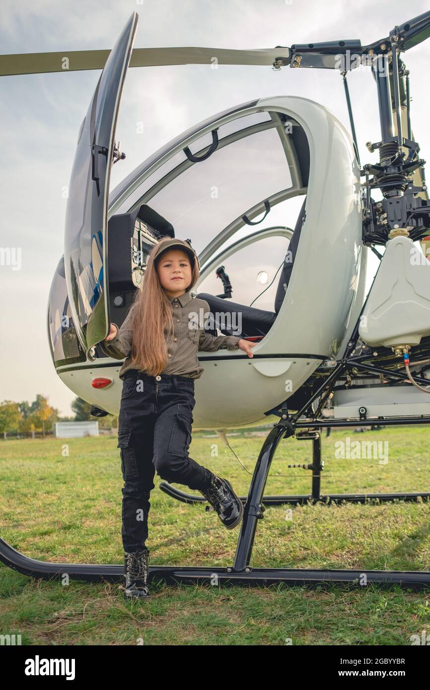 Brown-haired tween girl in visor cap standing near helicopter Stock ...