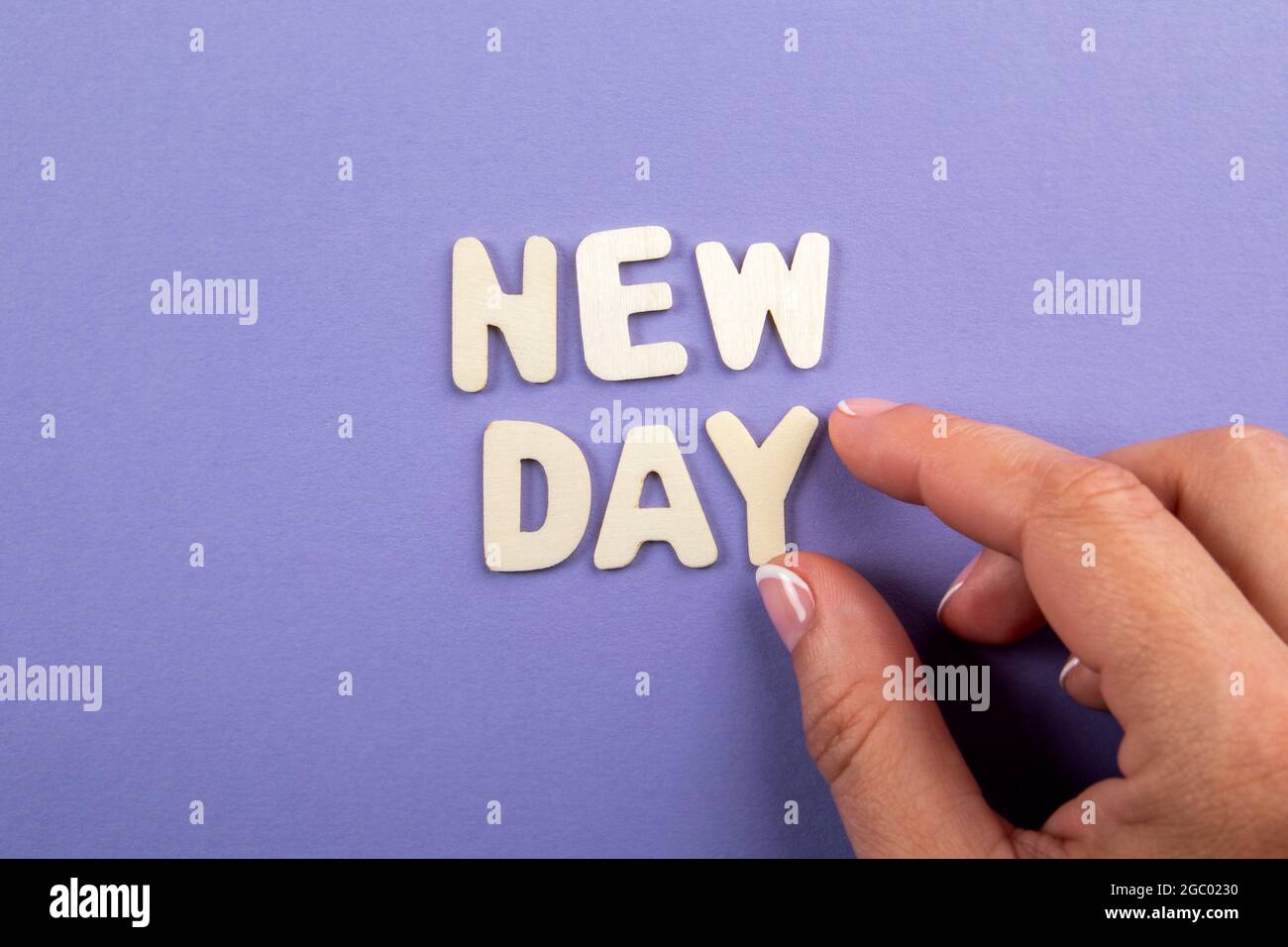 New Day. White letters and a woman's hand on a purple paper background ...