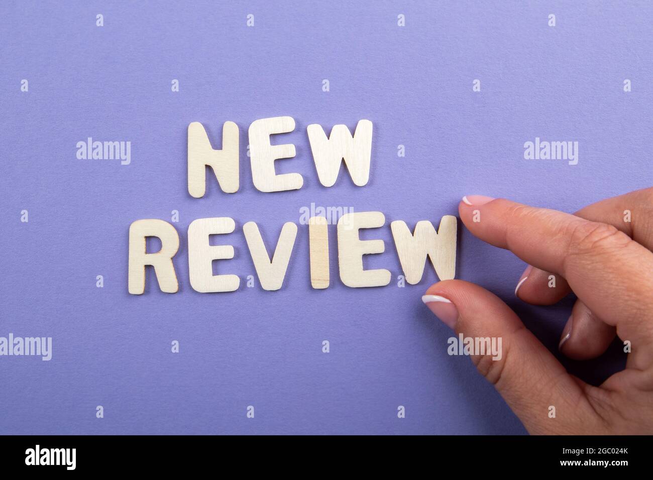 New Review. Word from white letters with a woman's hand on a purple ...