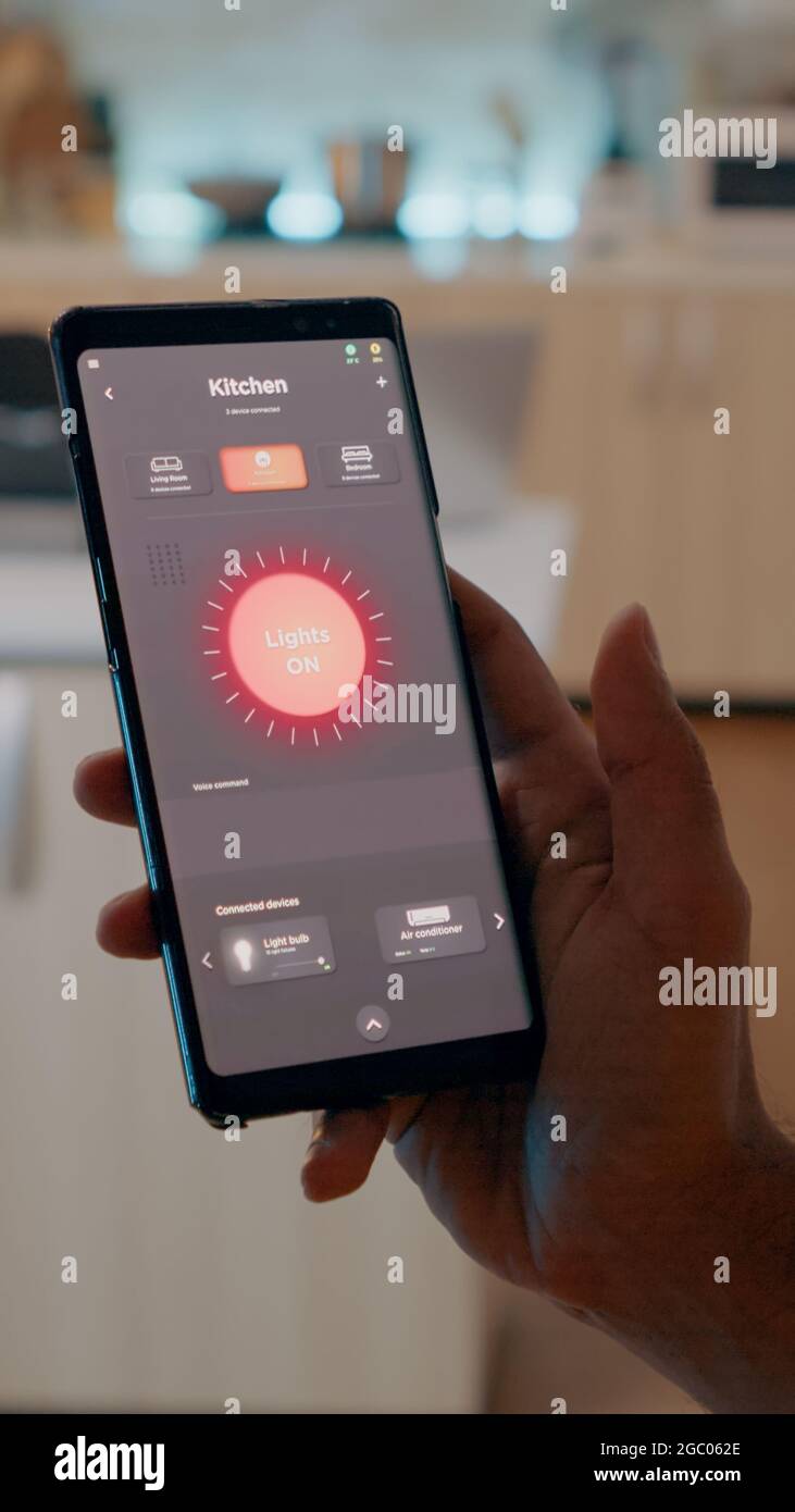 Person sitting in house with automation light system holding smartphone ...