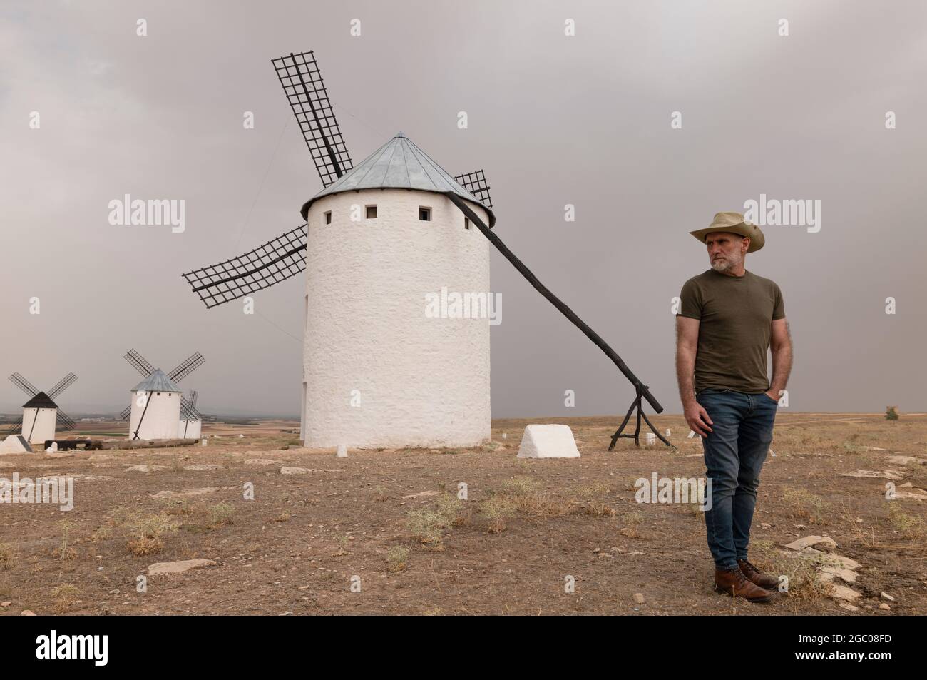 A man wearing a cowboy hat with windmills in the countryside Stock ...