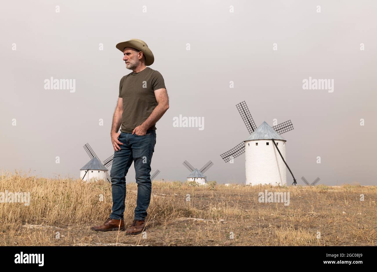 A man wearing a cowboy hat with windmills in the countryside Stock ...