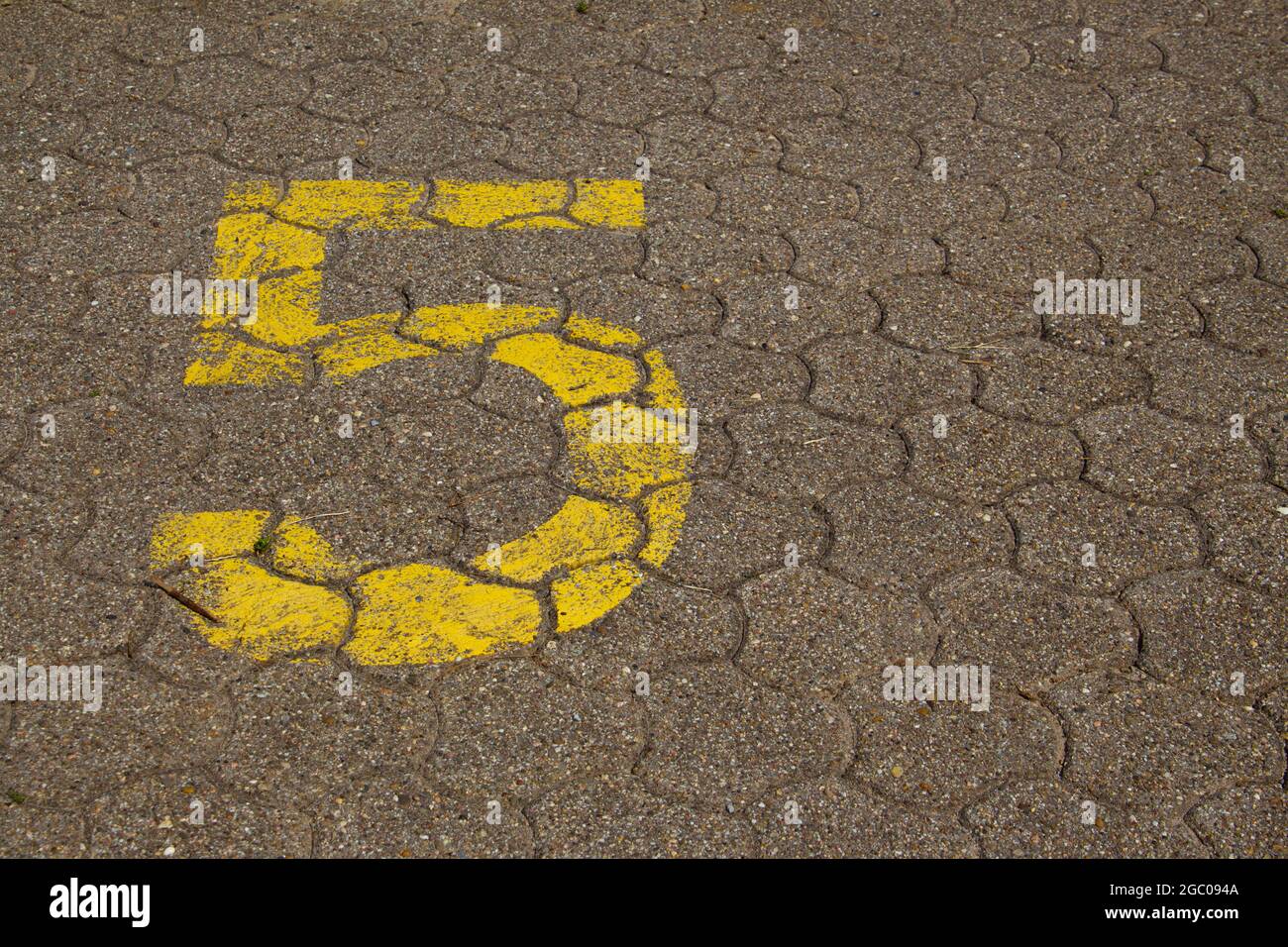 Yellow number 5 painted on concrete paving stones Stock Photo - Alamy
