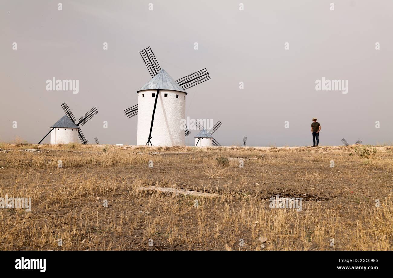 A man wearing a cowboy hat with windmills in the countryside Stock ...