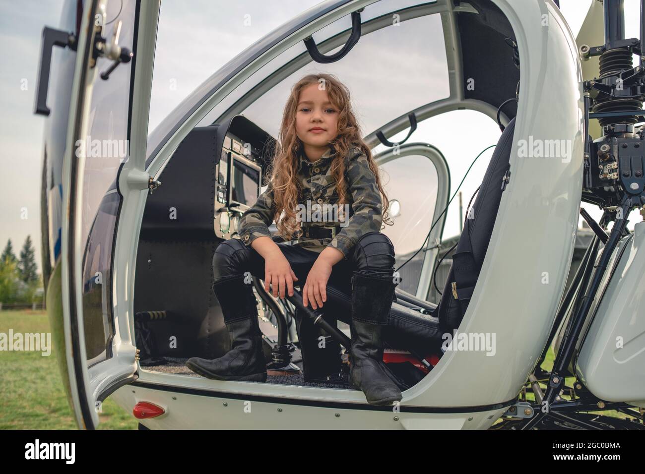 Confident preteen girl in camo style blouse sitting in open helicopter ...