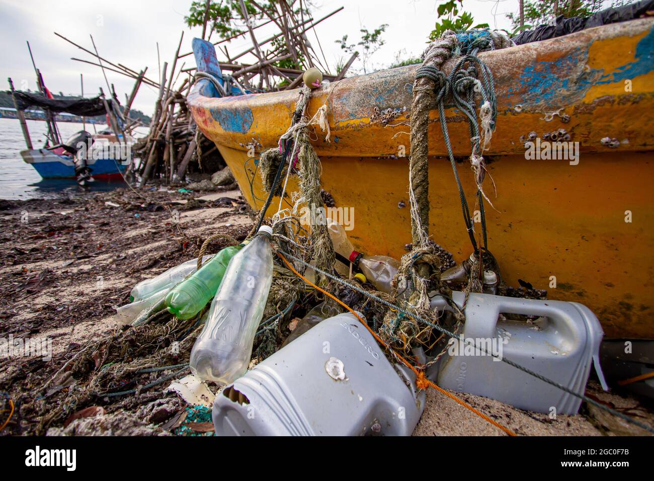Fishing gear and old yellow fishing boat on a beach with plastics and ...