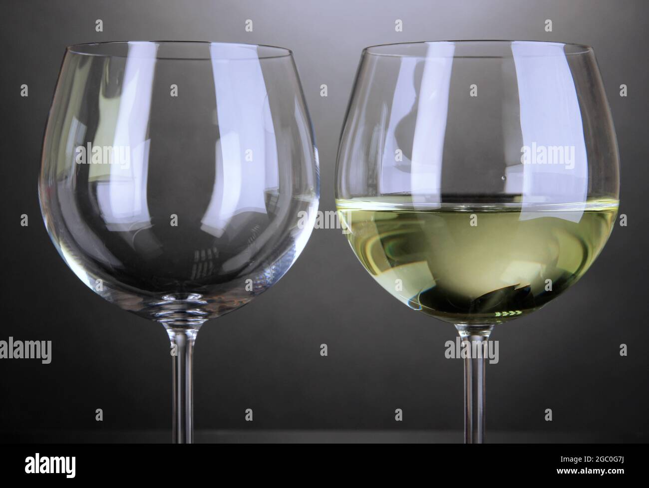 Empty and full wine glass on grey background Stock Photo - Alamy