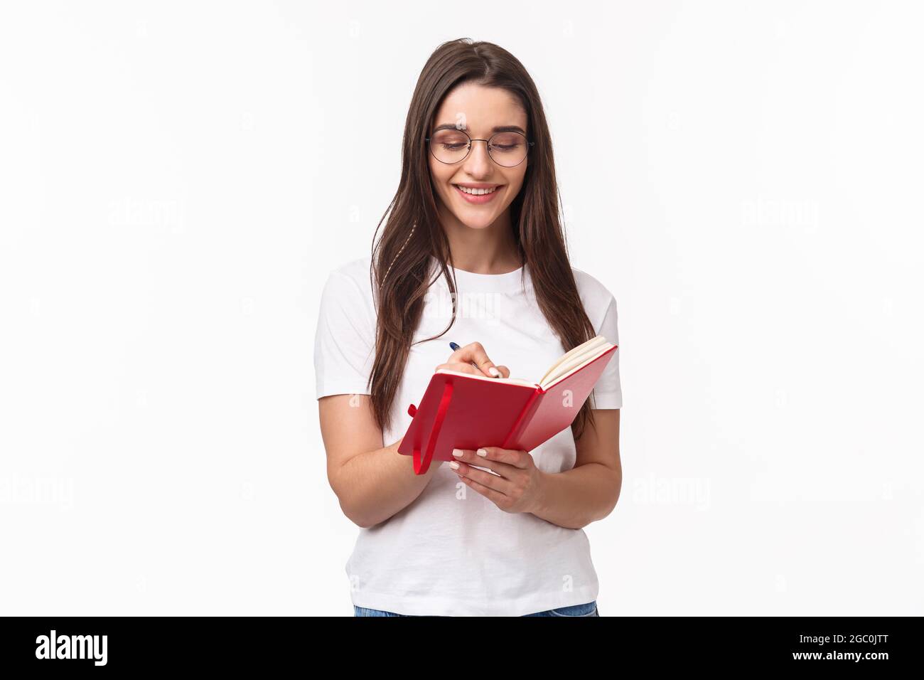 Portrait of smiling pretty caucasian girl writing in her diary, prepare ...