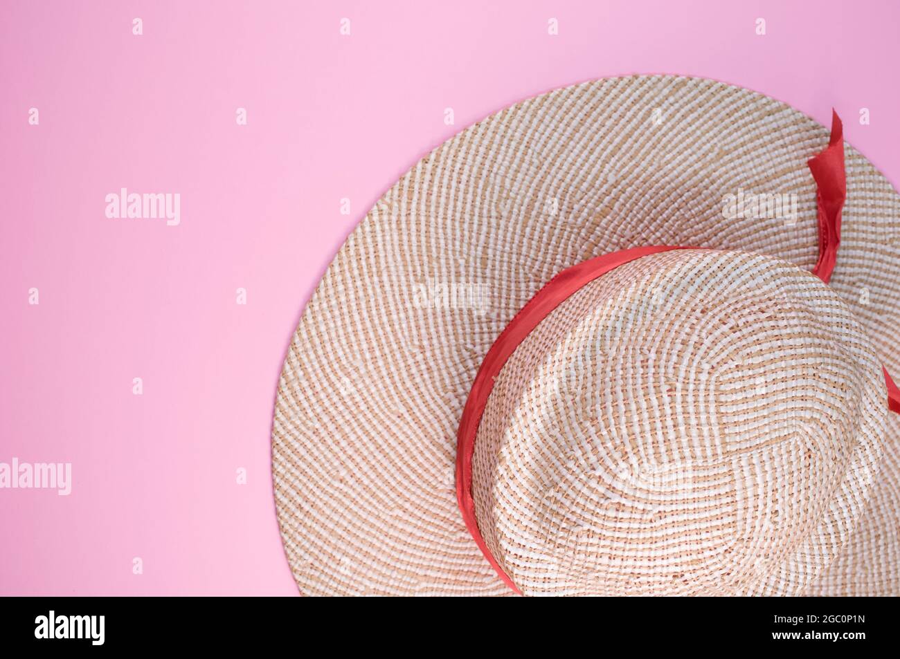 Top view of a straw hat with red ribbon isolated on a pink background ...