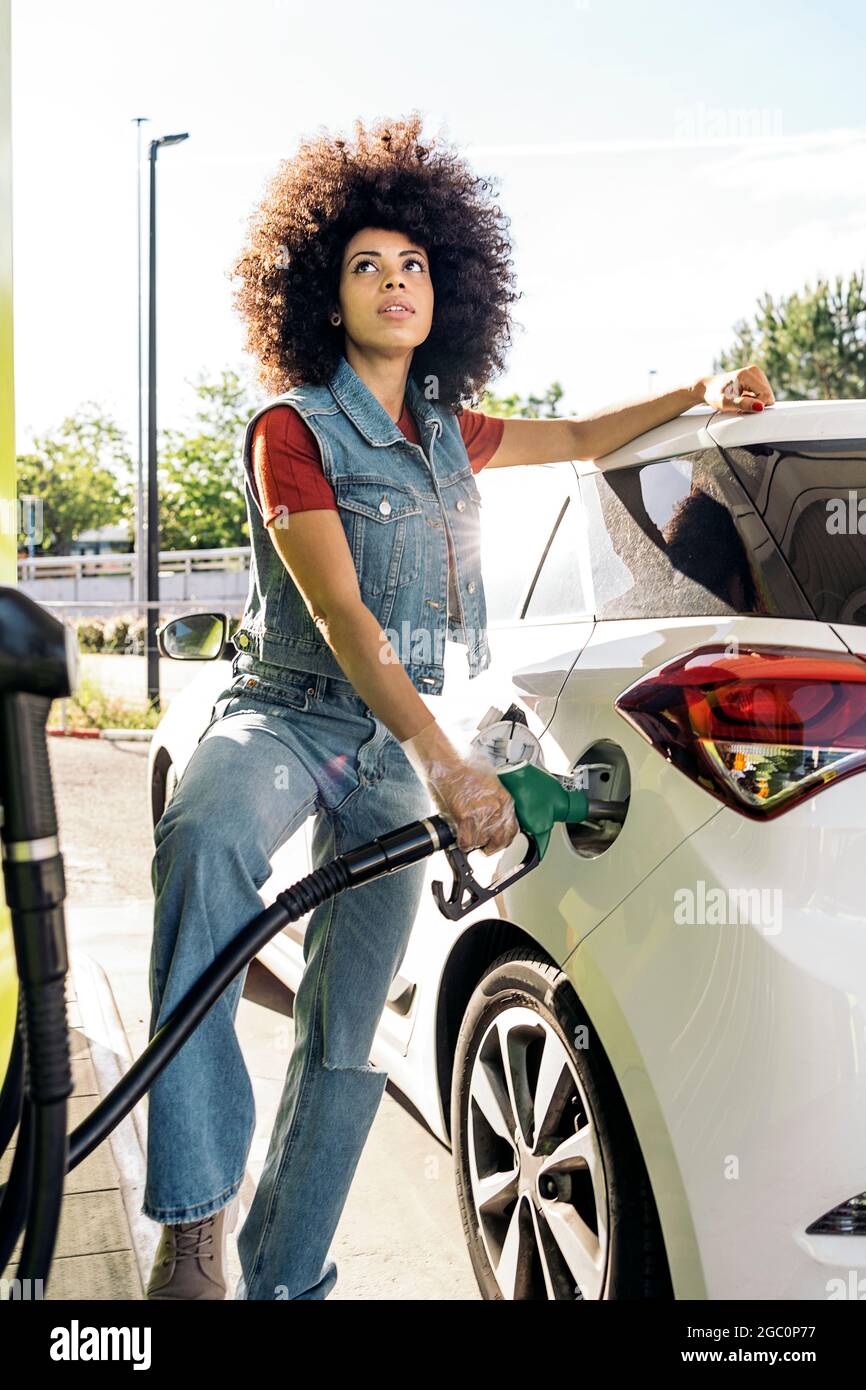 Beautiful woman with afro hair filling her car with gasoline at the gas ...