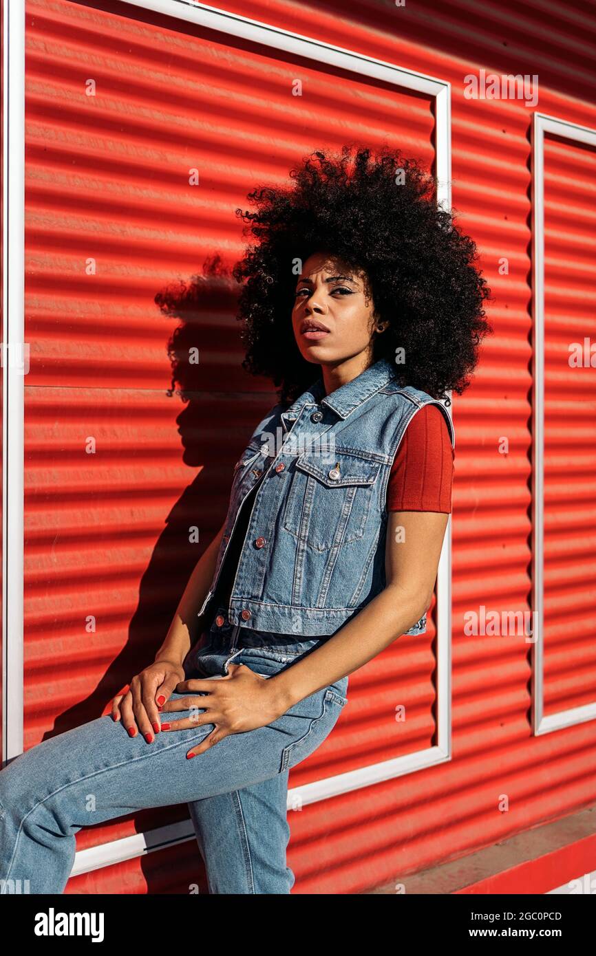 African woman with cool afro hair posing and looking at camera against ...