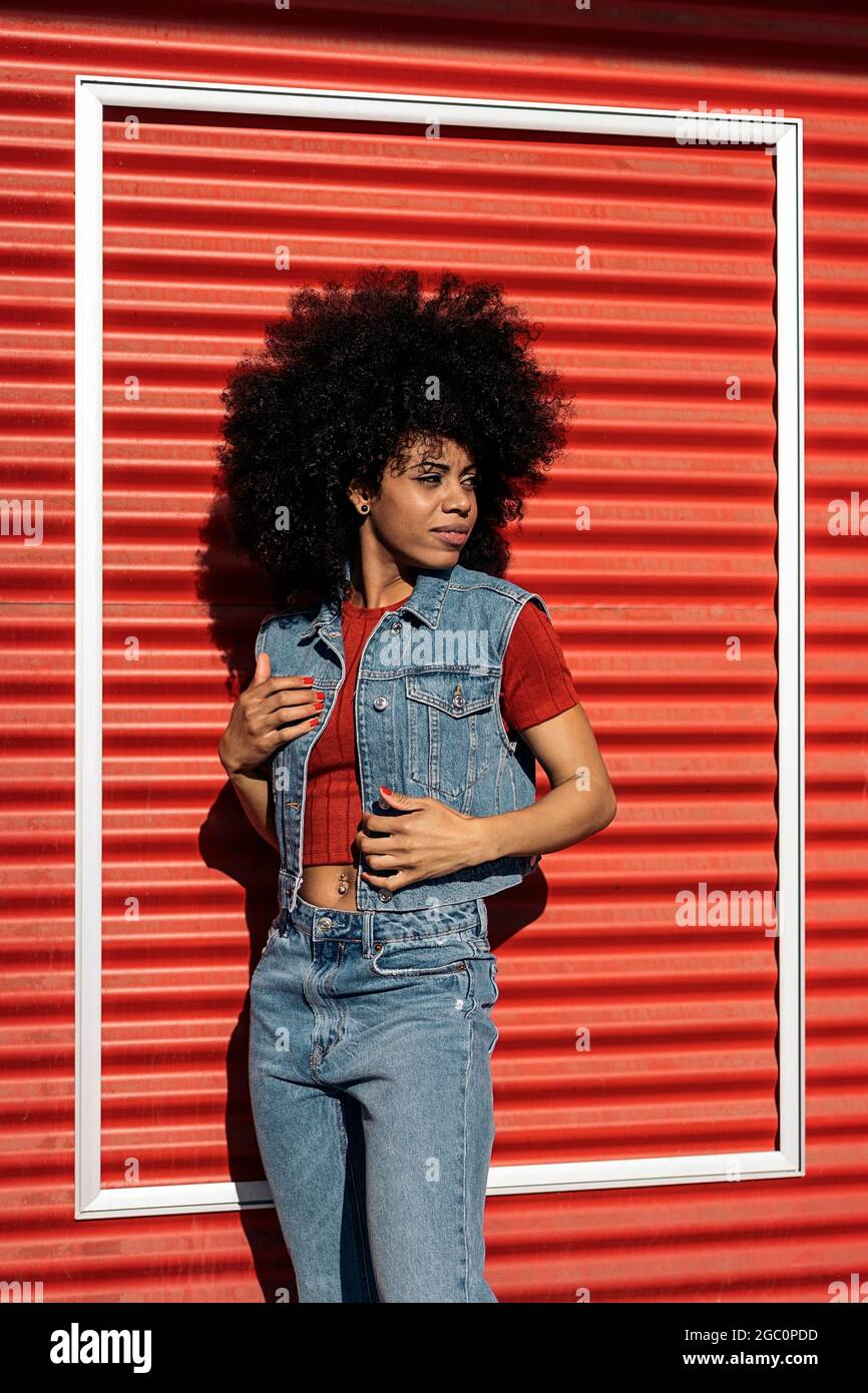 African woman with cool afro hair having fun and posing against red ...