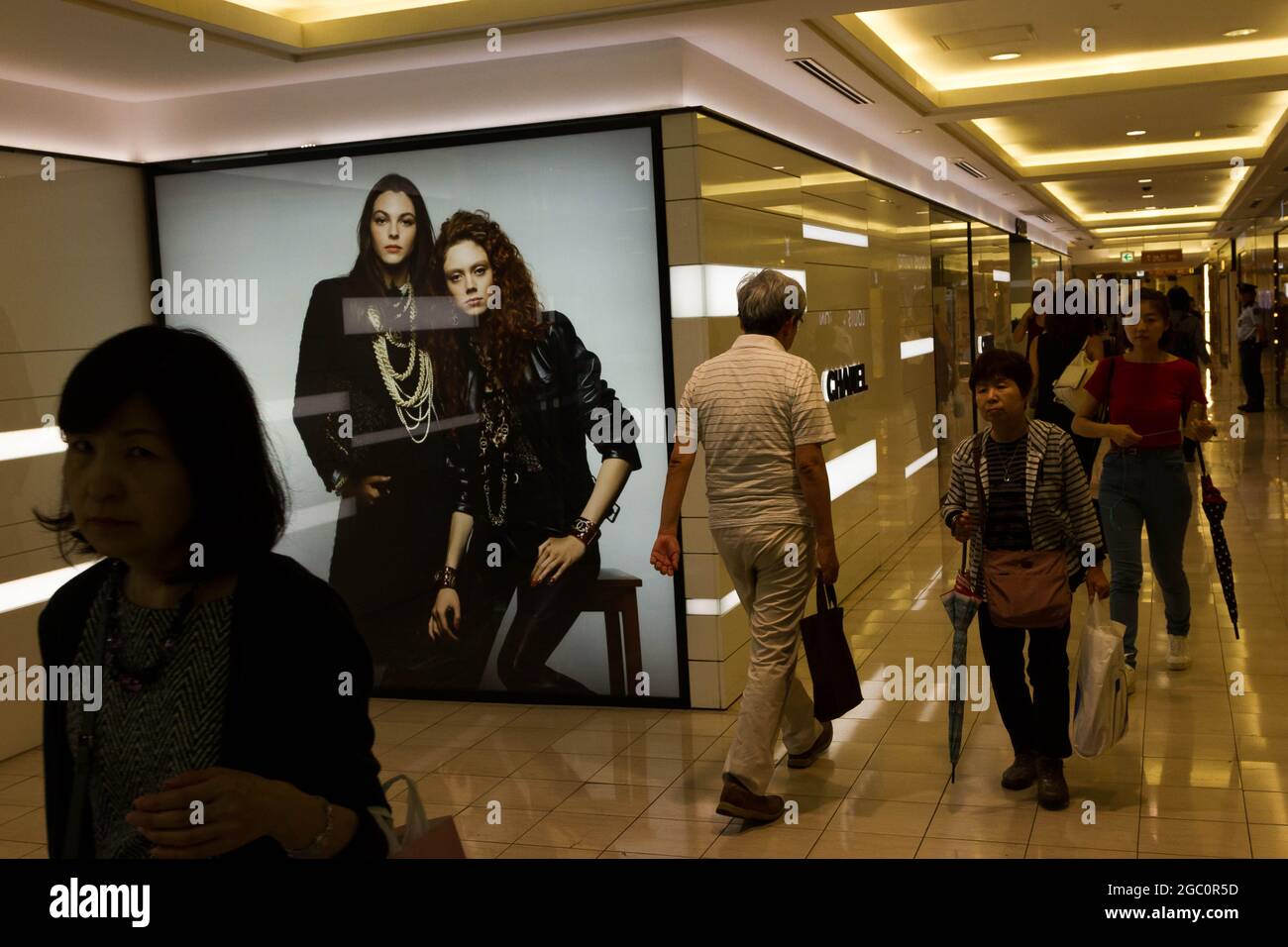 People walk past a Chanel Store at a shopping mall in Shinjuku, Tokyo ...