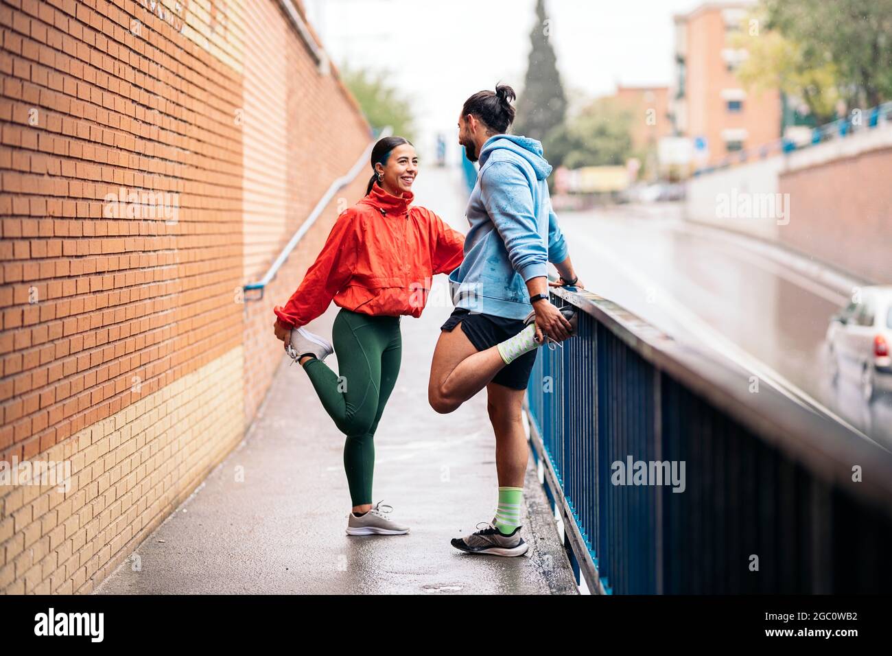 Young man and his female friend wearing sports clothes stretching after ...