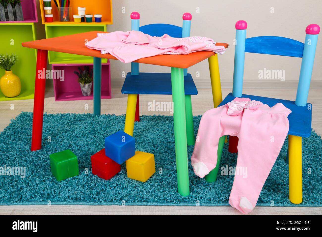 Small and colorful table and chairs with baby clothes Stock Photo - Alamy