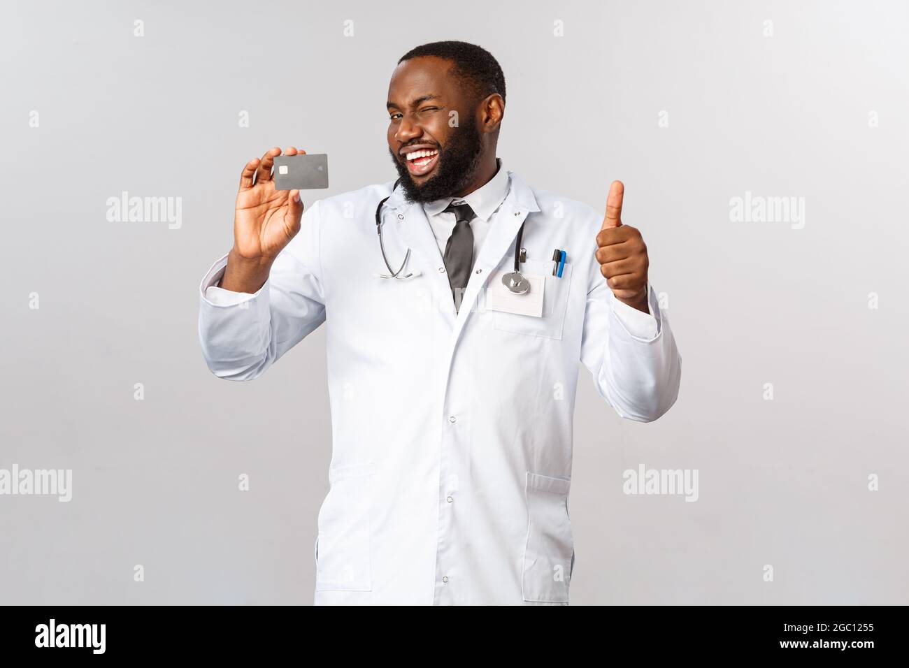 Satisfied, cheerful handsome african-american doctor in white coat ...