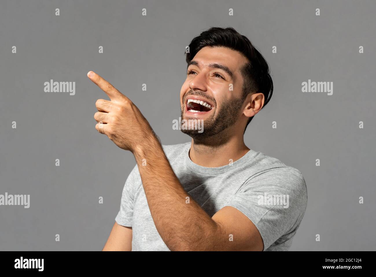 Portrait of happy smiling young Caucasian man looking and pointing hand ...