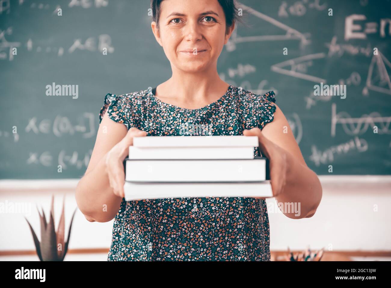 Back to school concept: teacher giving books to her studens in the ...