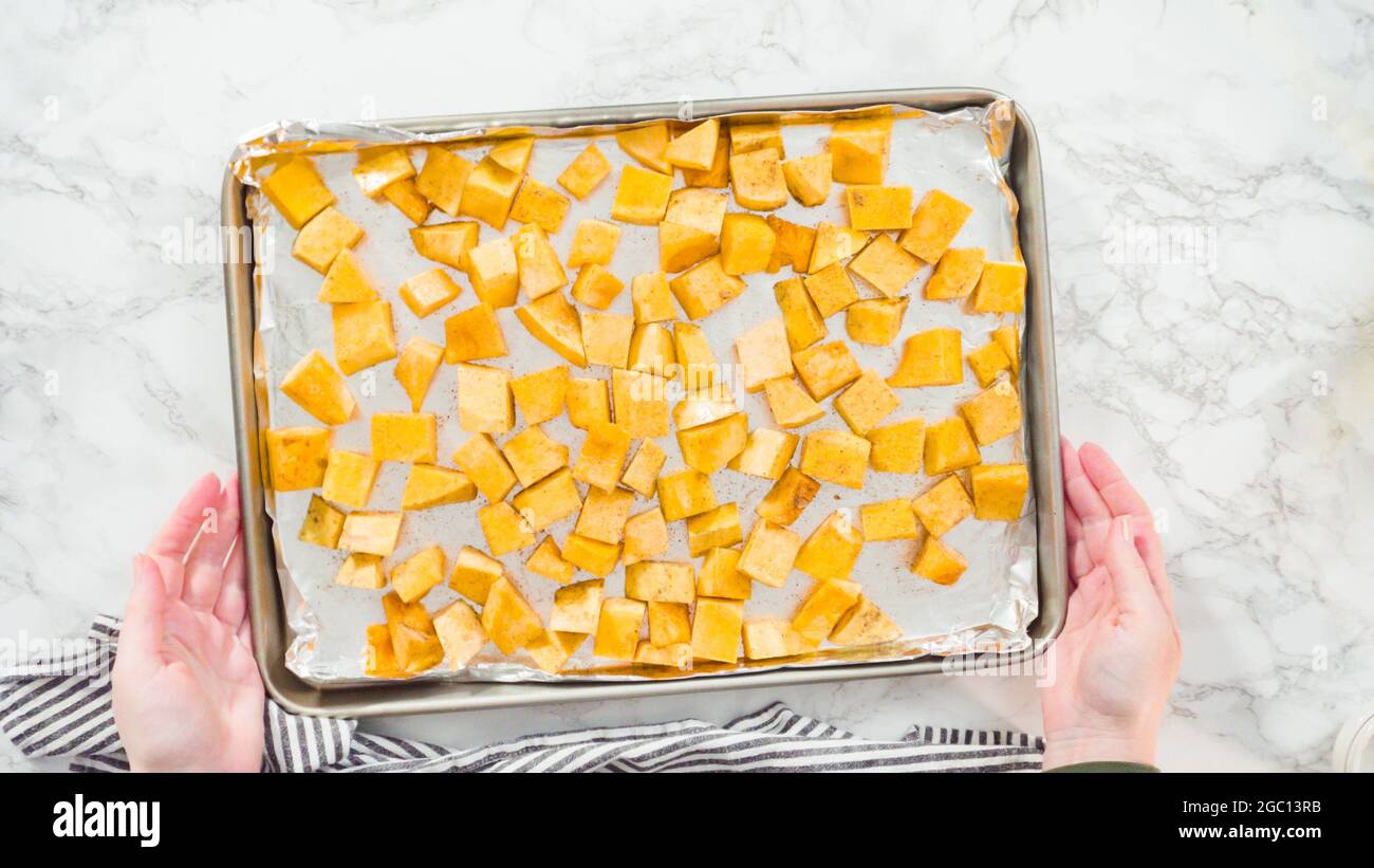 Seasoning butternut squash with oil, salt, and pepper for roasting in ...