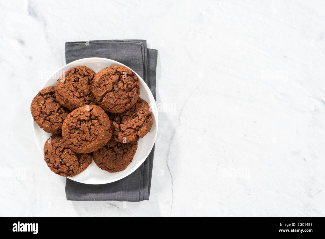 Flat lay. Freshly baked double chocolate chip cookies on a white plate ...