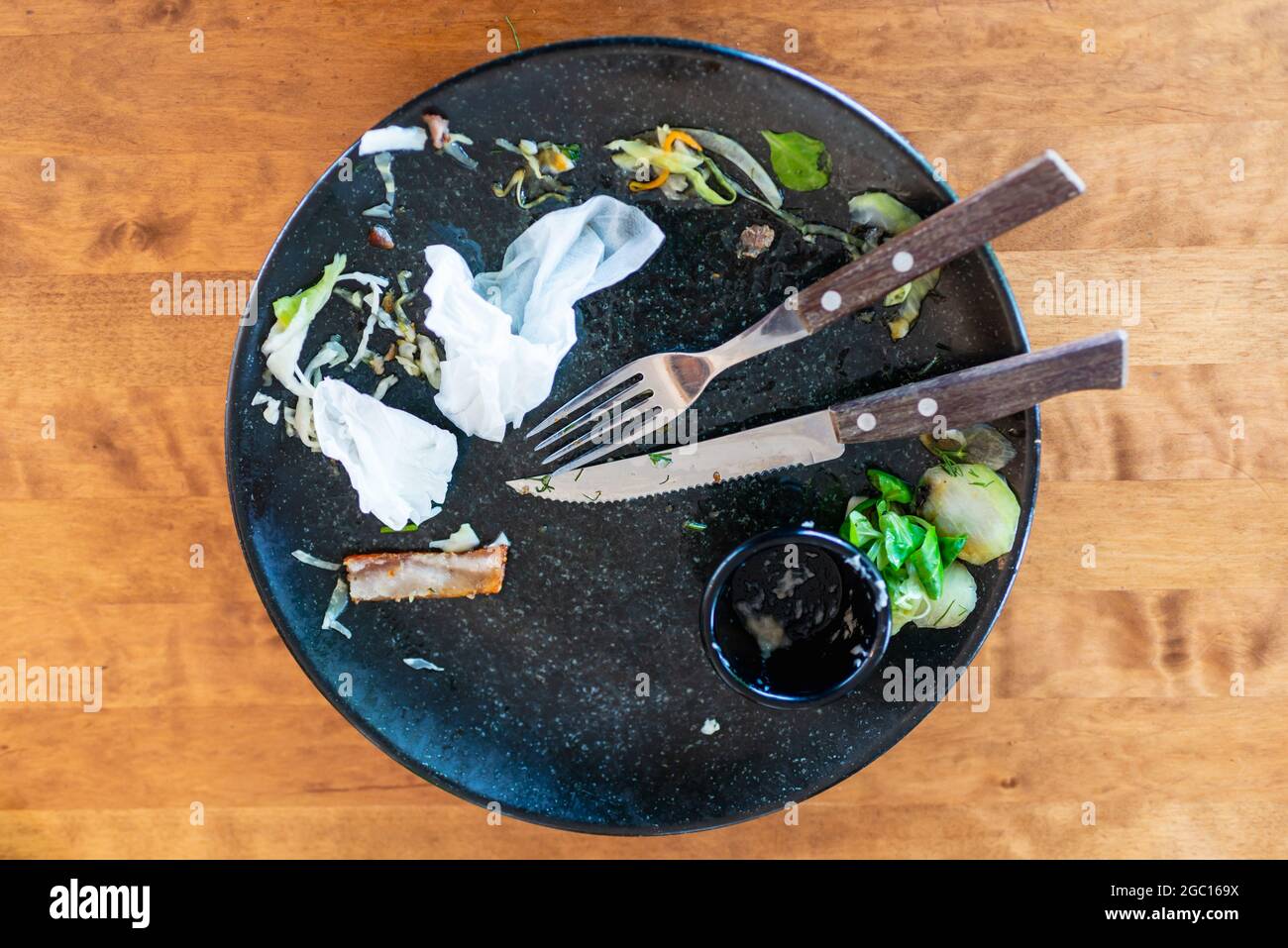 Empty dark plate left after dinner.Dirty dish after eaten with knife ...