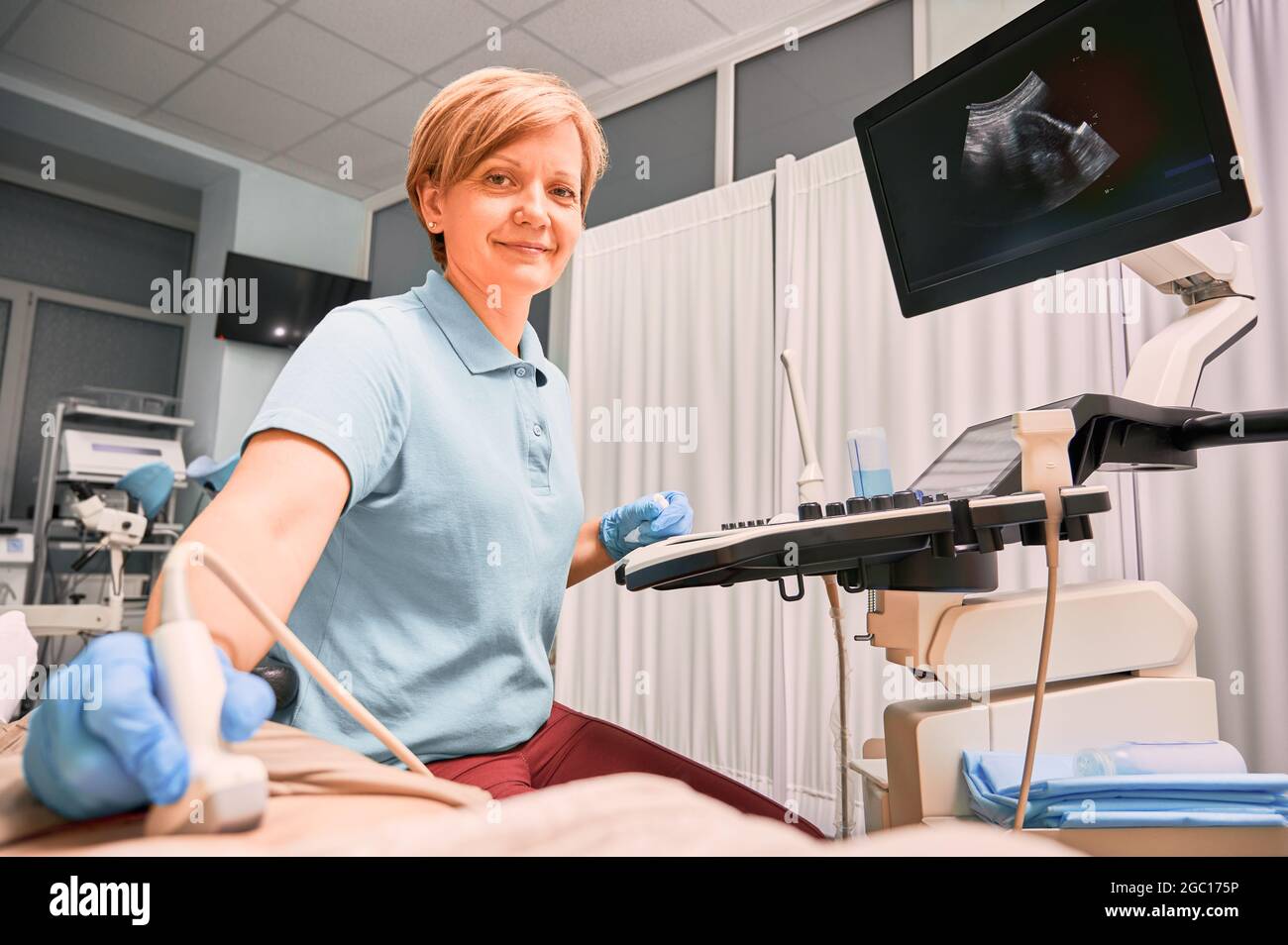 Female sonographer examining patient with ultrasound scanner. Doctor ...