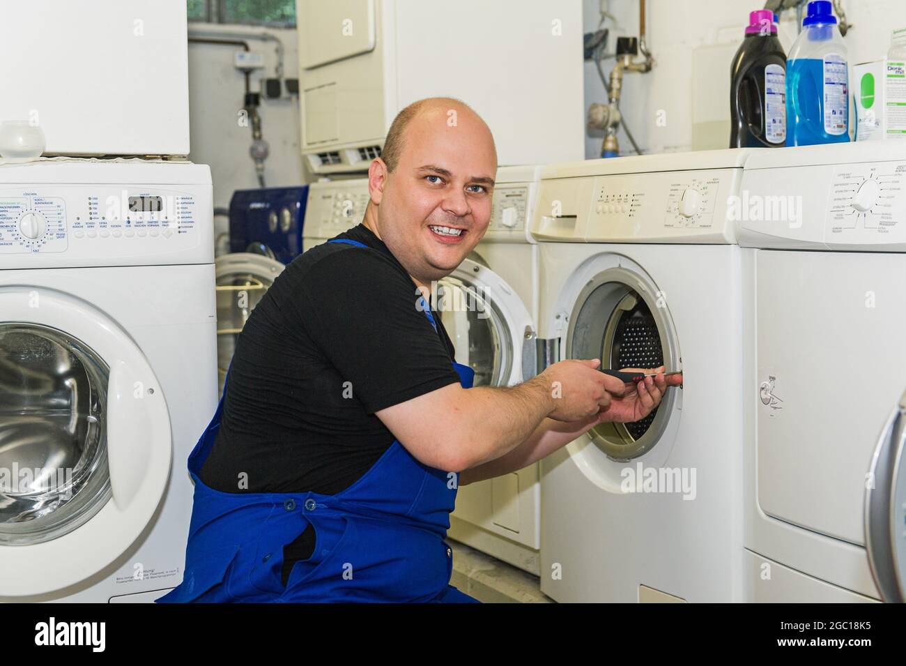 repairman repairing a washing machine in a laundry room Stock Photo - Alamy